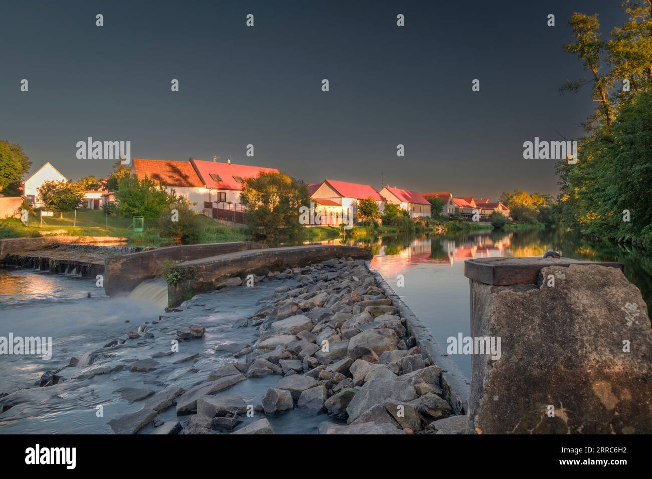 Big weir in Budweis with blue sky and small countryside buildings in ...