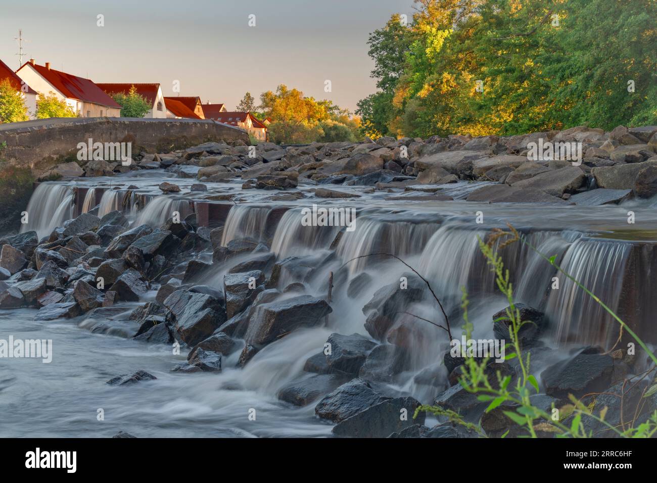 Big weir in Budweis with blue sky and small countryside buildings in ...