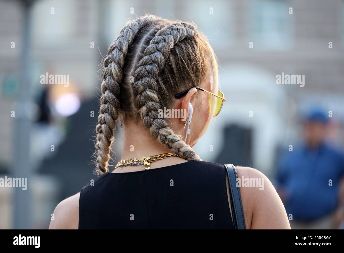 Girl with braided pigtails walking on a street. Female hairstyle and ...