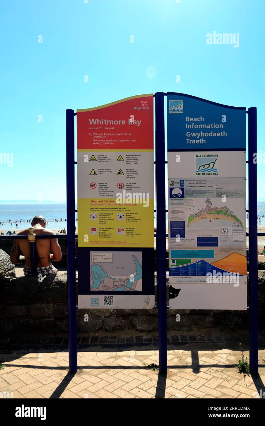 Sign for Whitmore Bay beach information at Barry Island, and man with ...
