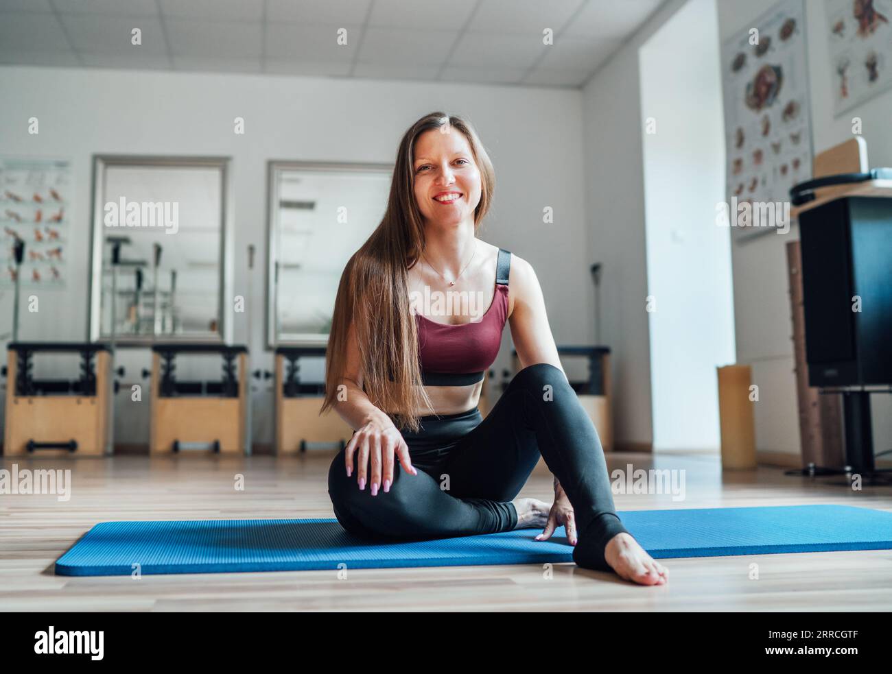 Beautiful fit-shape female dressed sporty sitting and sincerely smiling ...