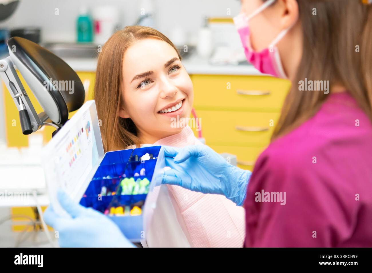 Young beautiful patient with perfect smile listening to the dentist how ...