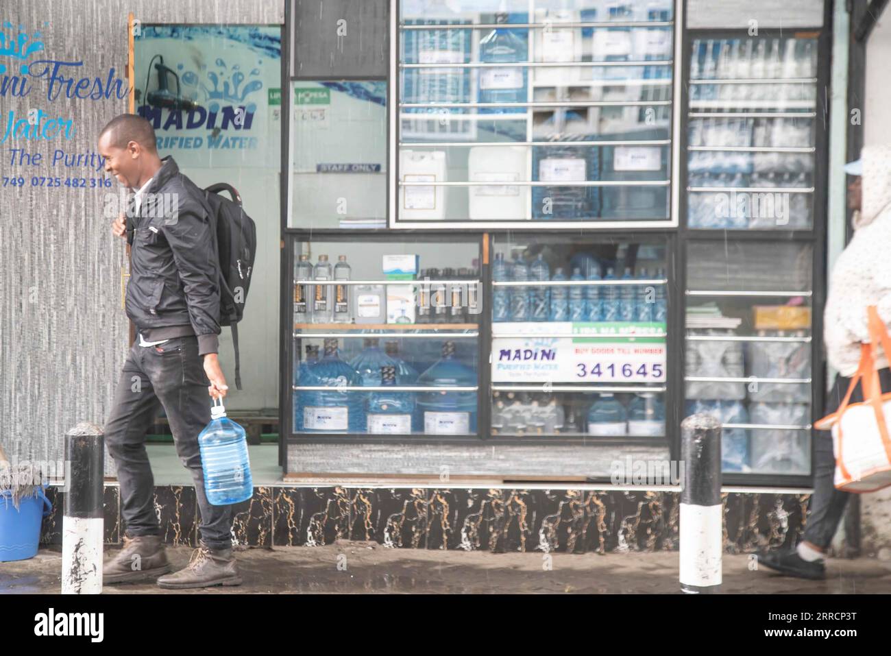 A customer carries his refilled water bottle from a vending station in ...