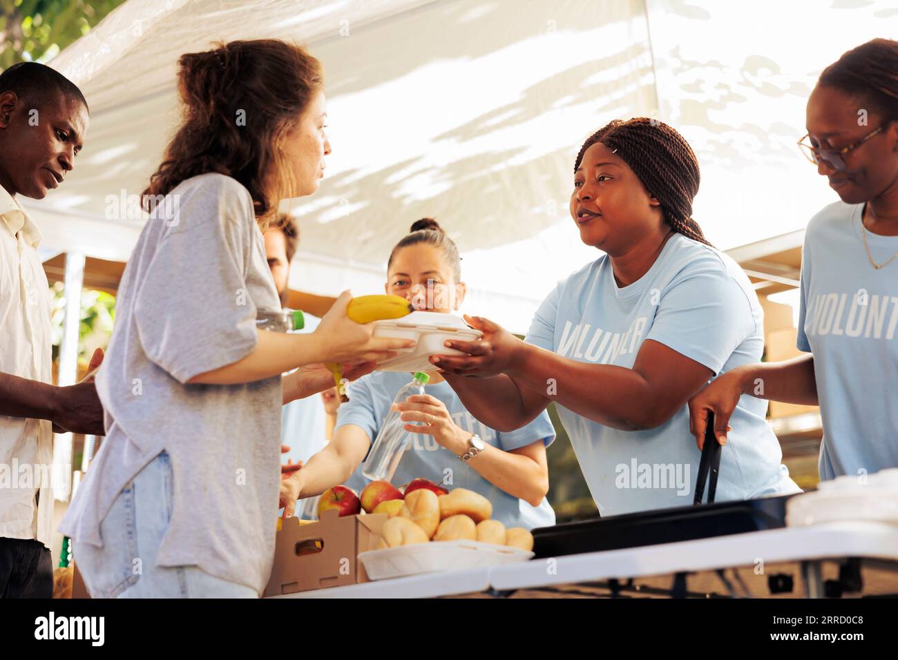 Multiracial volunteers handing out meal donations to the needy at a ...