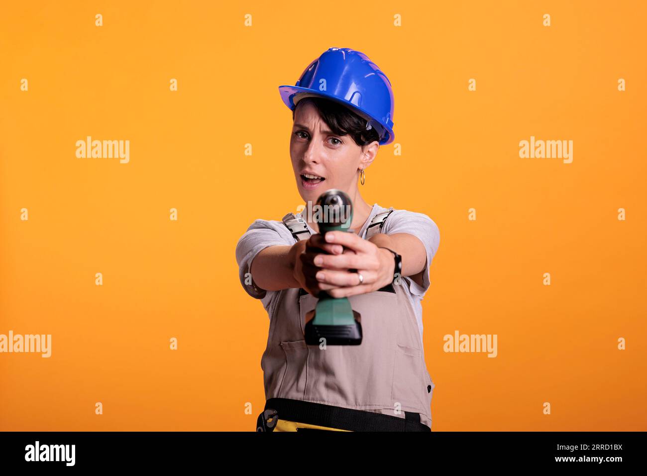 Industrial engineer acting crazy with drilling screw gun in studio ...