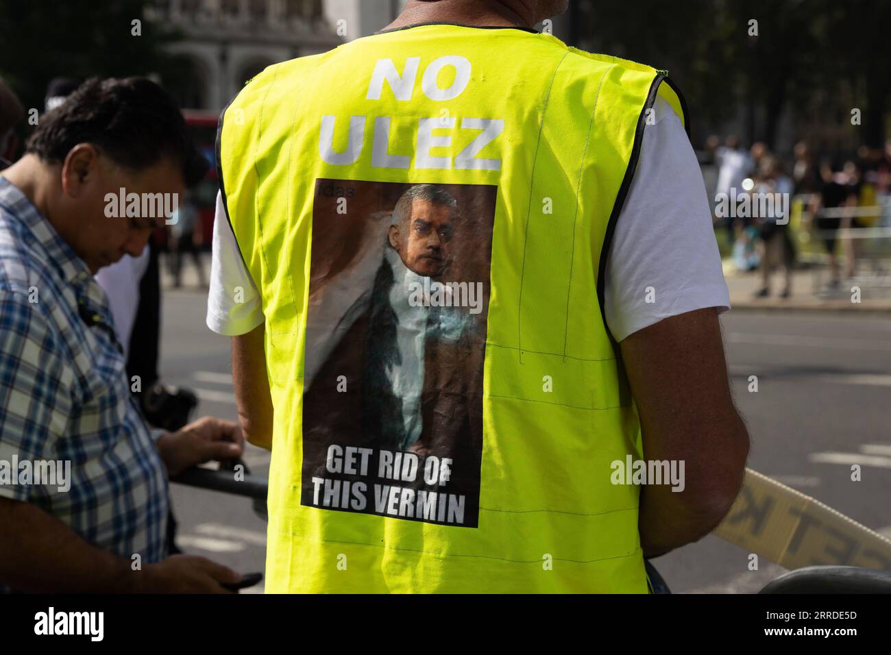 An anti-ULEZ protestor wears a high visibility jacket with the words ...