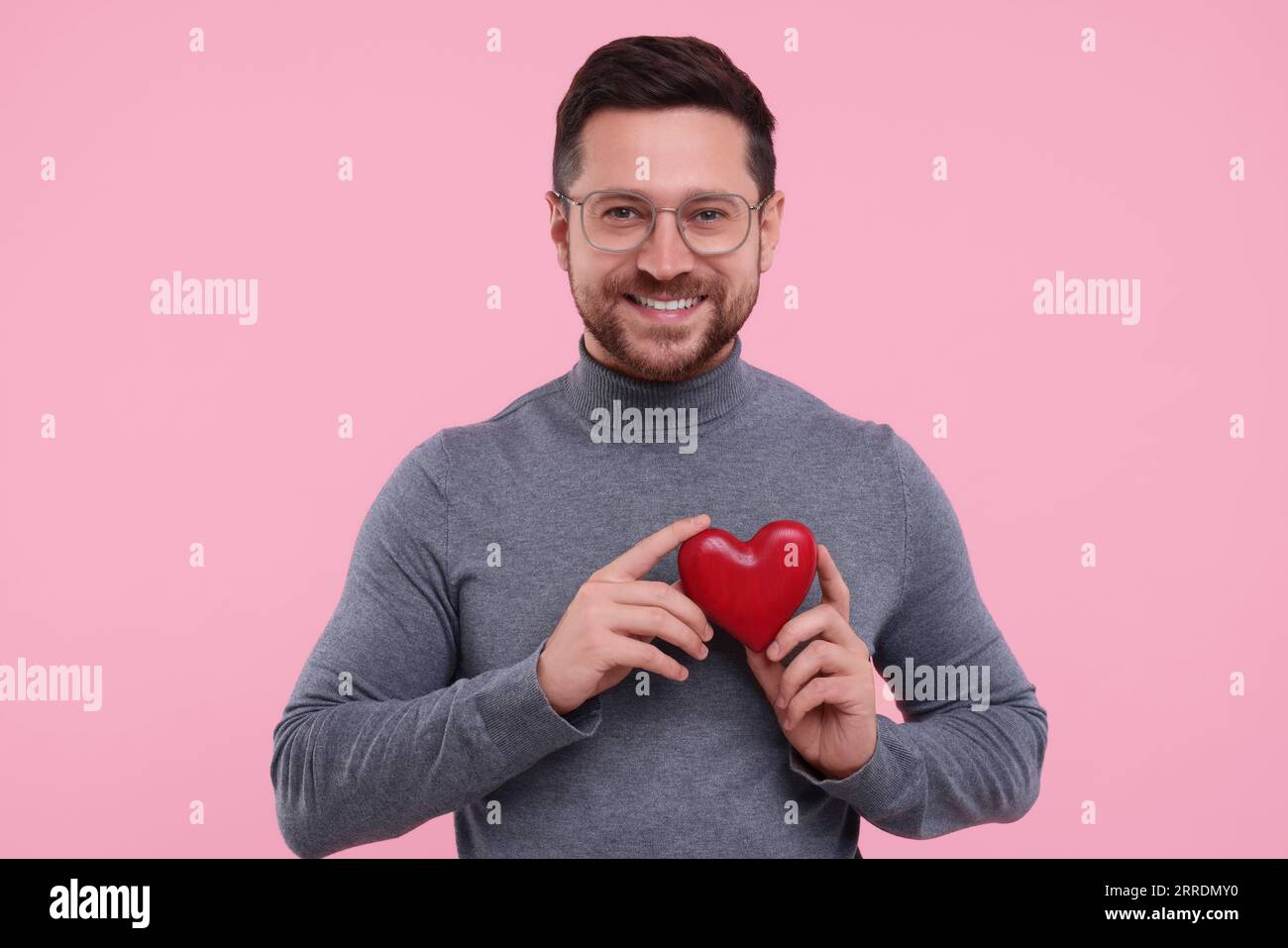 Happy man holding red heart on pink background Stock Photo - Alamy