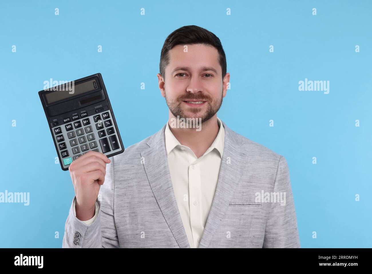 Happy accountant with calculator on light blue background Stock Photo ...