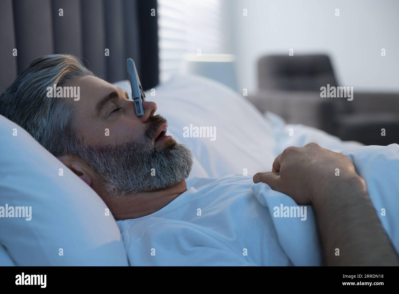 Man sleeping with clothespin on his nose in bed at home. Problem with ...