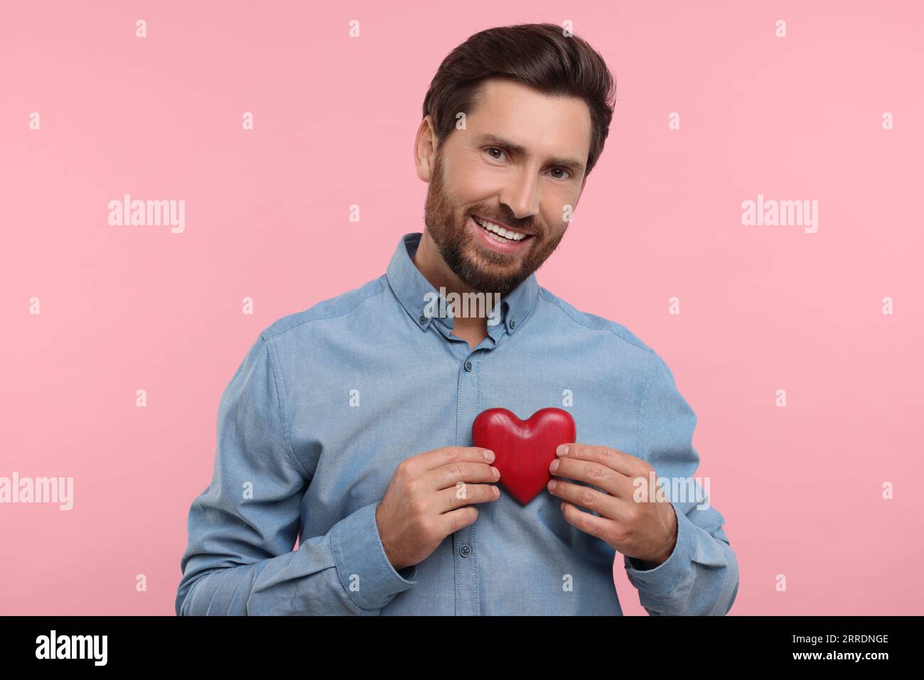 Happy man holding red heart on pink background Stock Photo - Alamy
