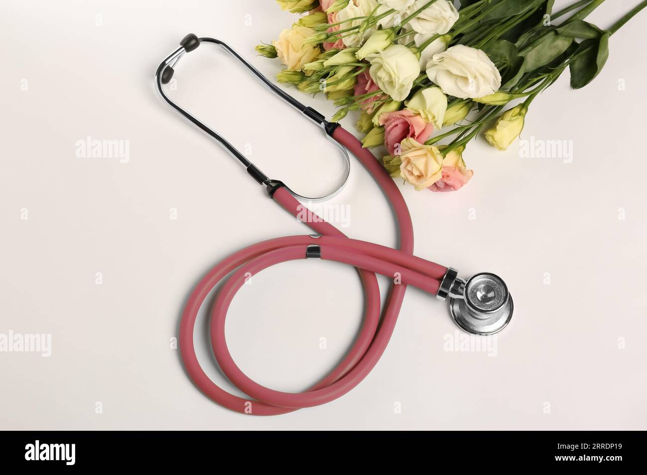 Stethoscope and eustoma flowers on white background, flat lay. Happy ...