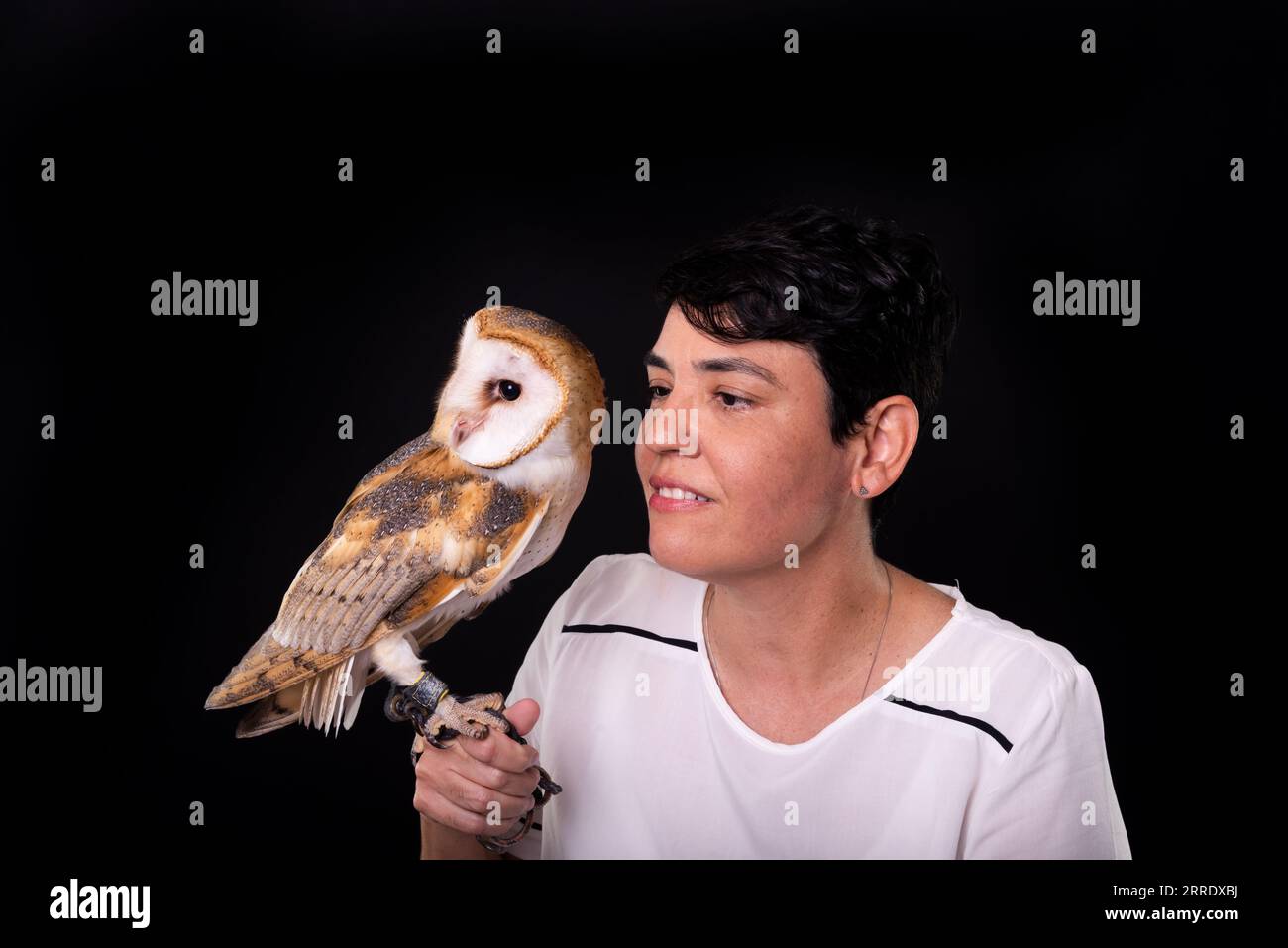 A beautiful woman looking fondly at the owl. Studio photo with black ...