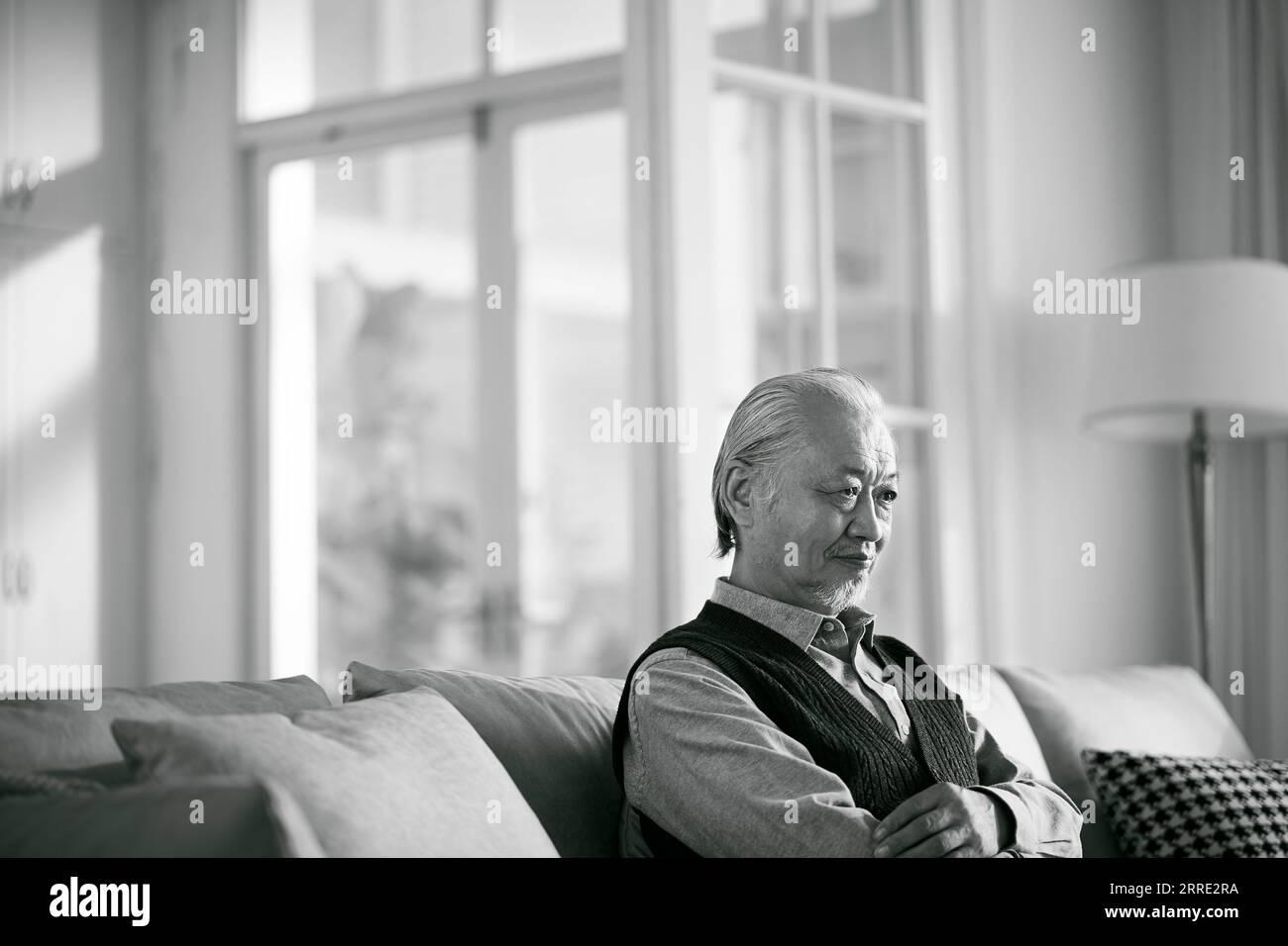 sad asian old man sitting alone on couch in living room at home, black ...