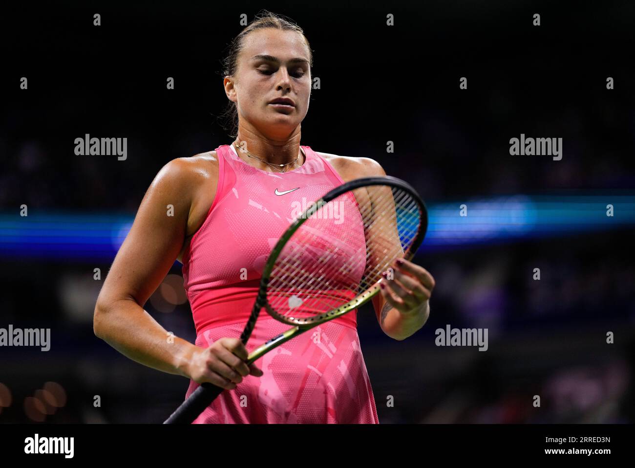 Aryna Sabalenka, of Belarus, adjusts the strings on her racket between ...