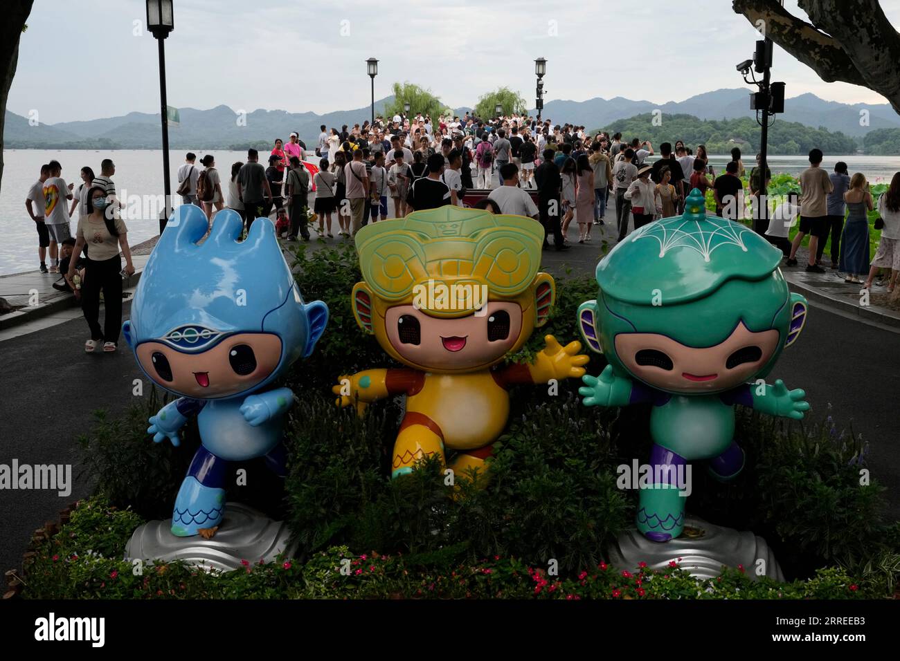 Tourists visiting the Westlake pass near official mascots of the 19th ...