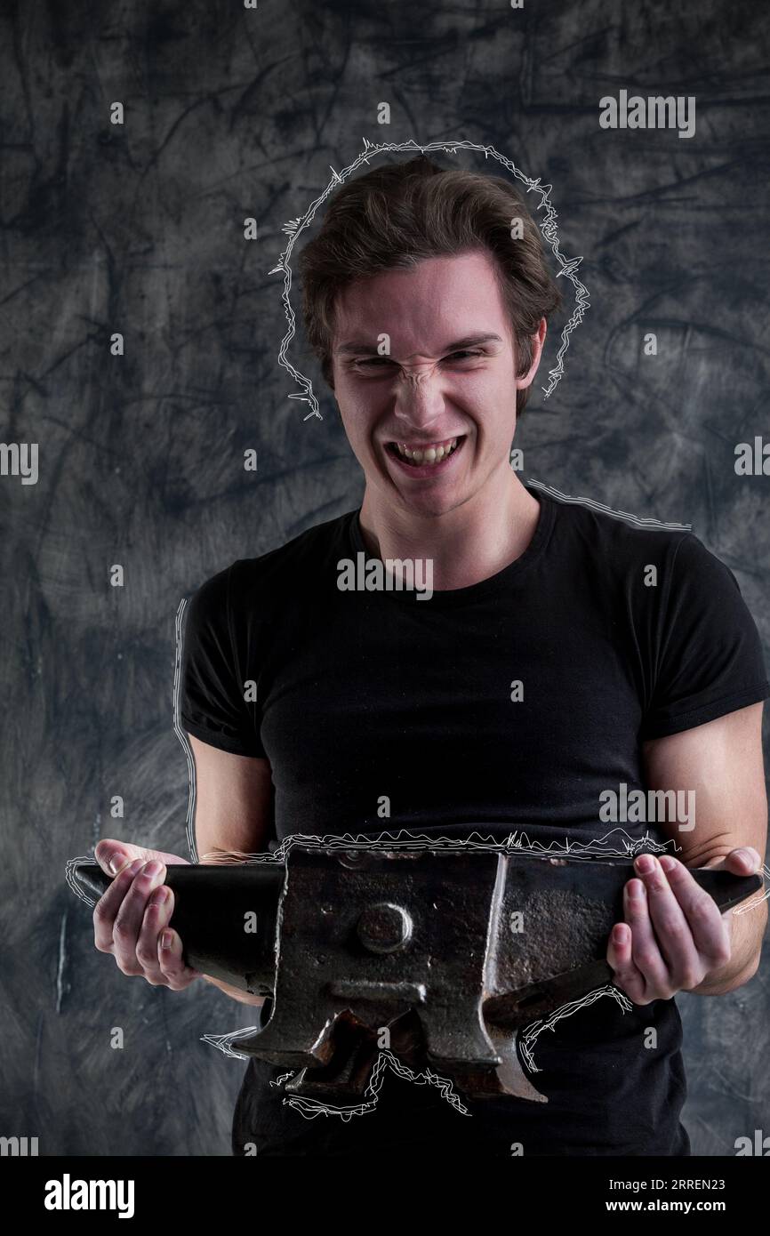 On a dramatic grunge-black backdrop, a young man in a black shirt lifts ...