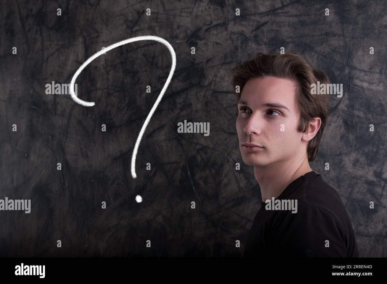 Light-brown-haired man, black shirt, stands before a grunge blackboard. Eyes lifted to a graphic ...