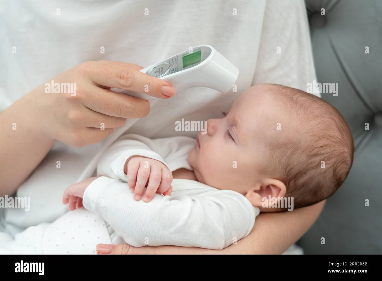 Mother and electronic thermometer ensure infant's safety. Concept of ...