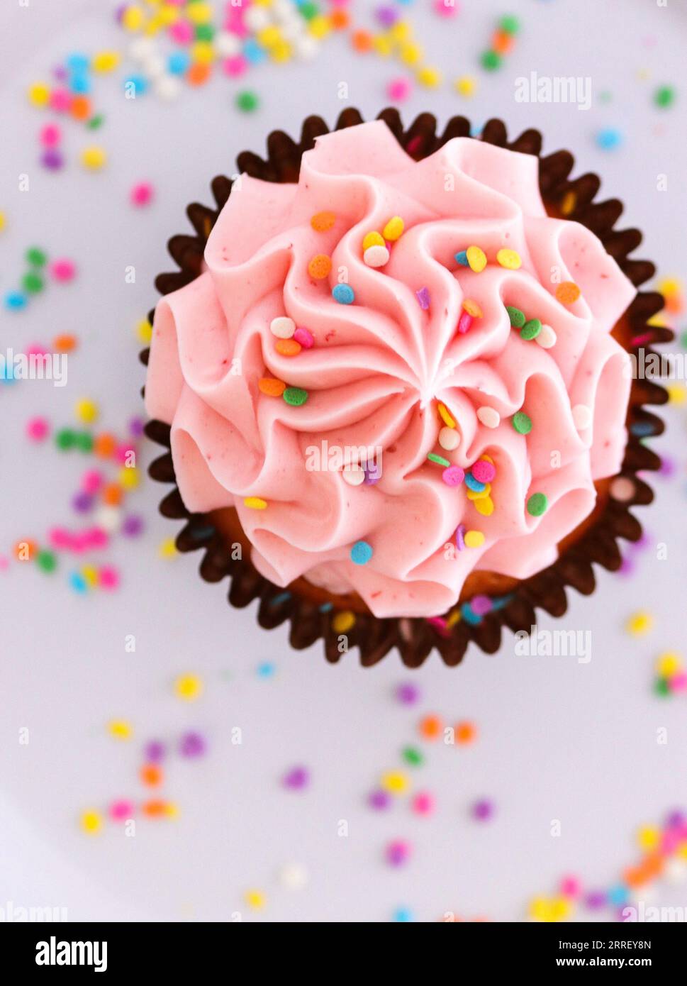 Vanilla cupcake with pink frosting and candy sprinkles Stock Photo - Alamy