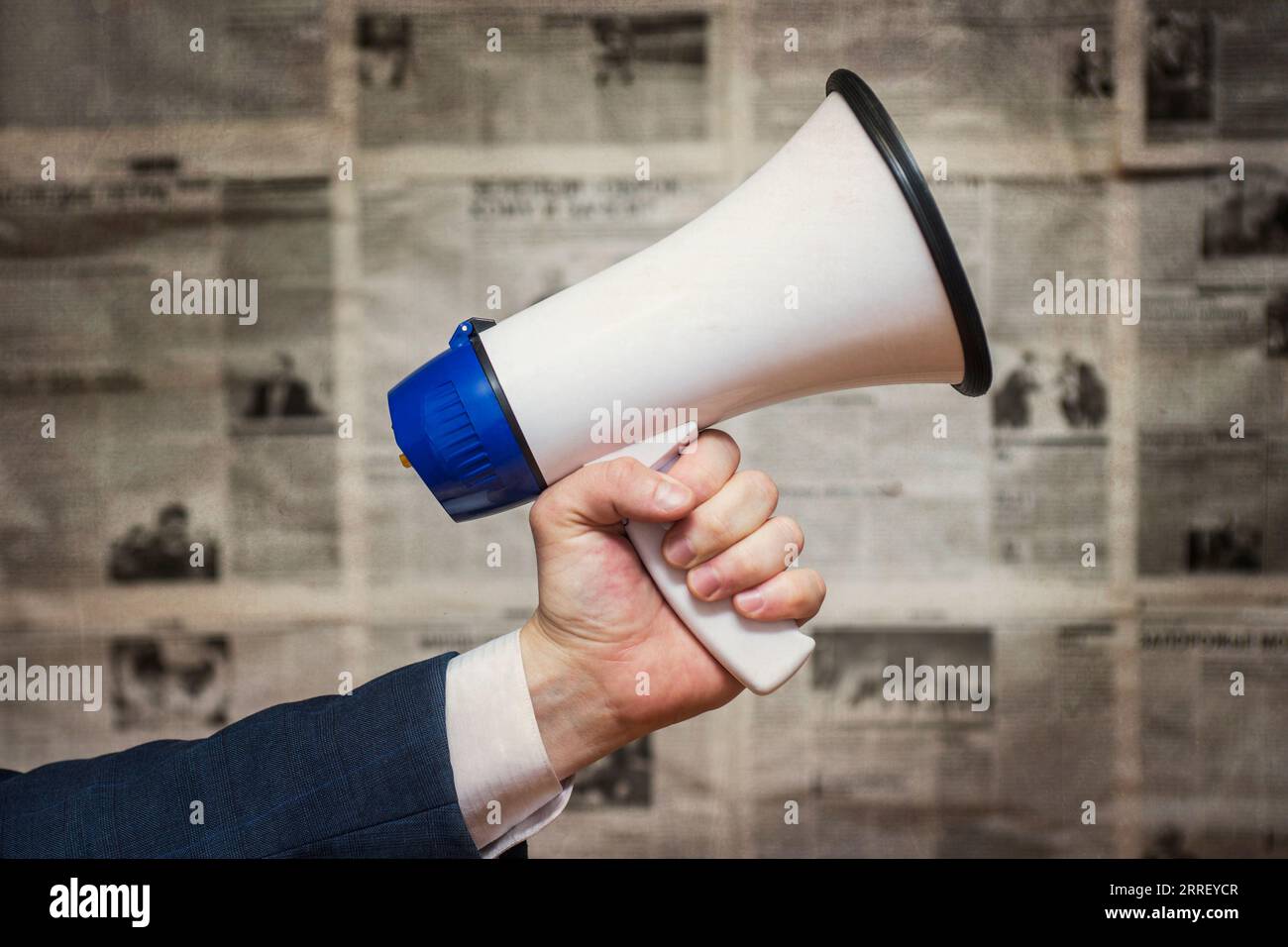 A man holding a megaphone on background of newspapers. News message ...