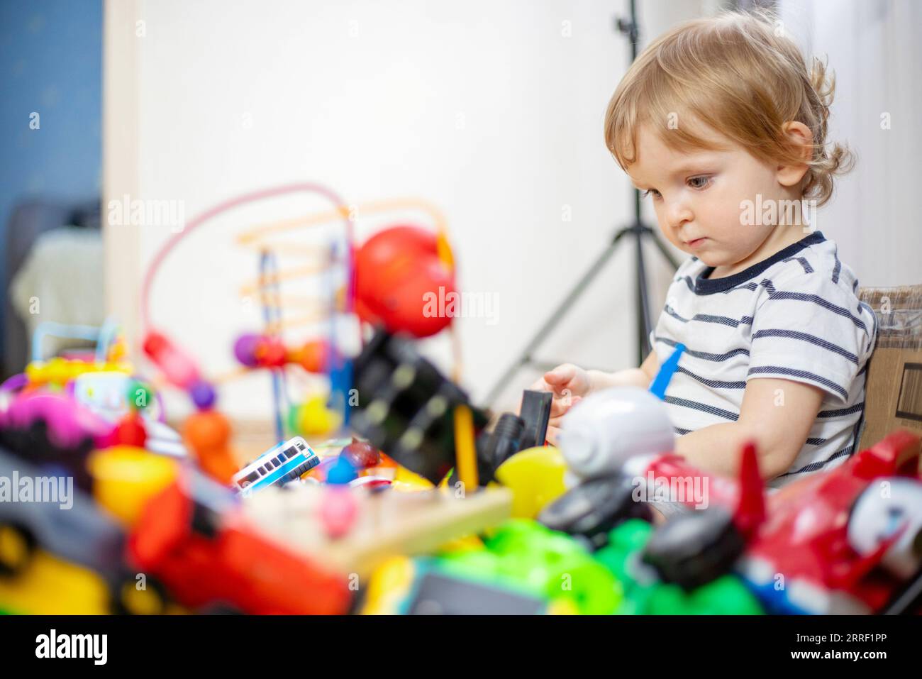 A huge bunch of different and colored toys in front of playful child ...