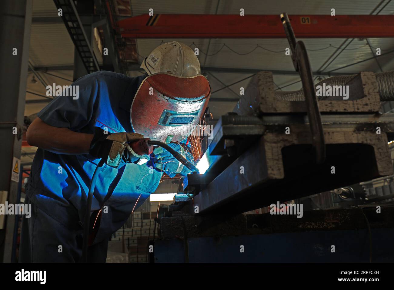 The workers are welding the mechanical parts in the factory Stock Photo ...