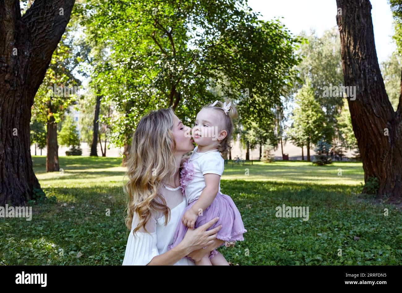 Mother and daughter walk in the summer city park. Childhood, leisure and people concept - happy ...