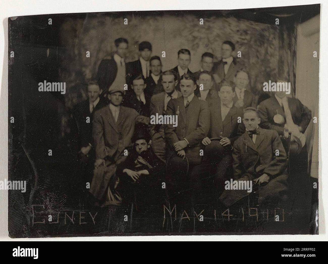 Group portrait of seventeen men in front of a painted background canvas ...