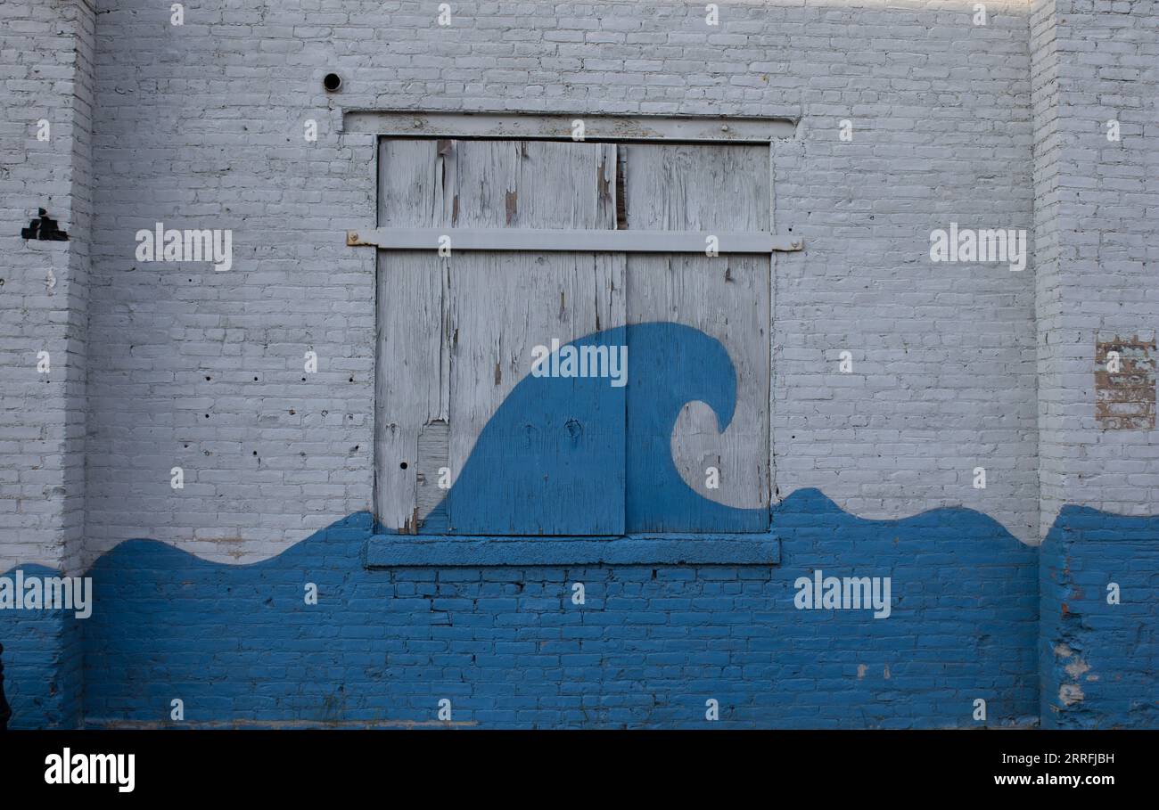 A close-up of a window with its shutter with a blue ocean wave painting ...