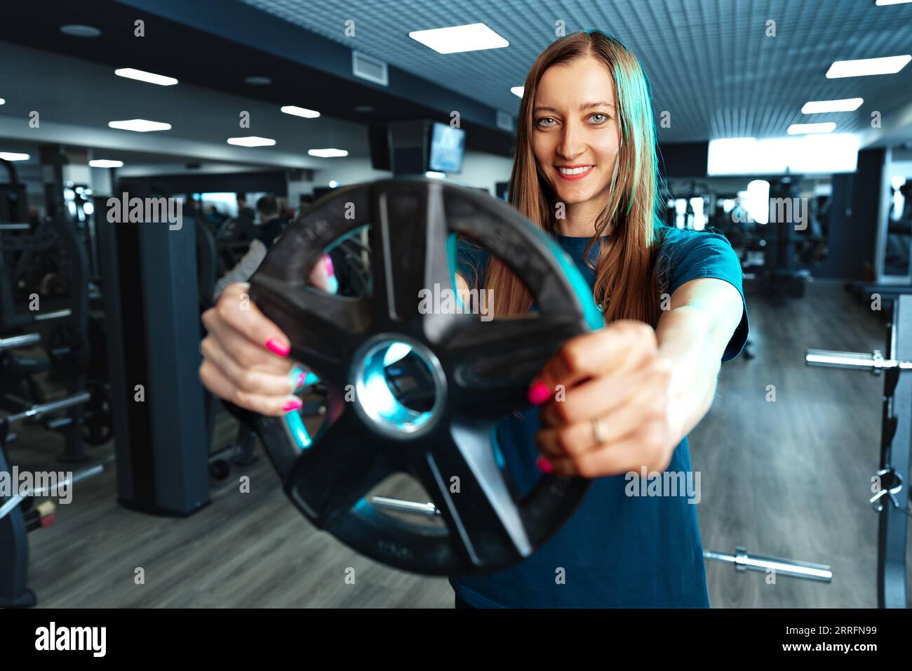 Sporty woman exercising with heavy weights plate in a gym Stock Photo ...
