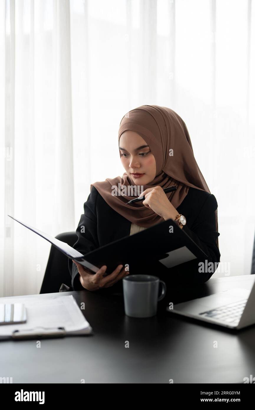 A professional and thoughtful millennial Asian Muslim businesswoman or ...