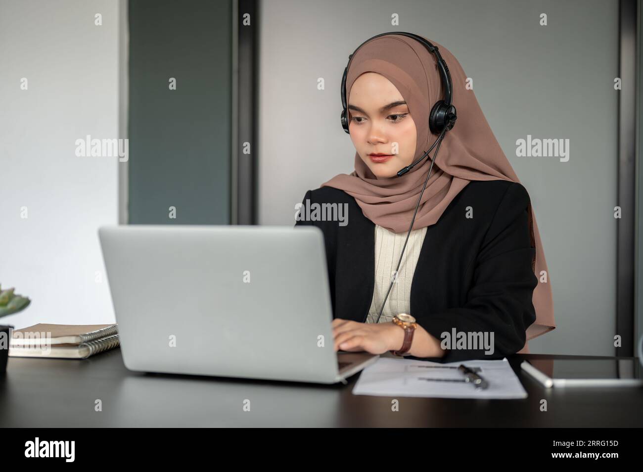A focused and professional Asian Muslim female call centre operator ...