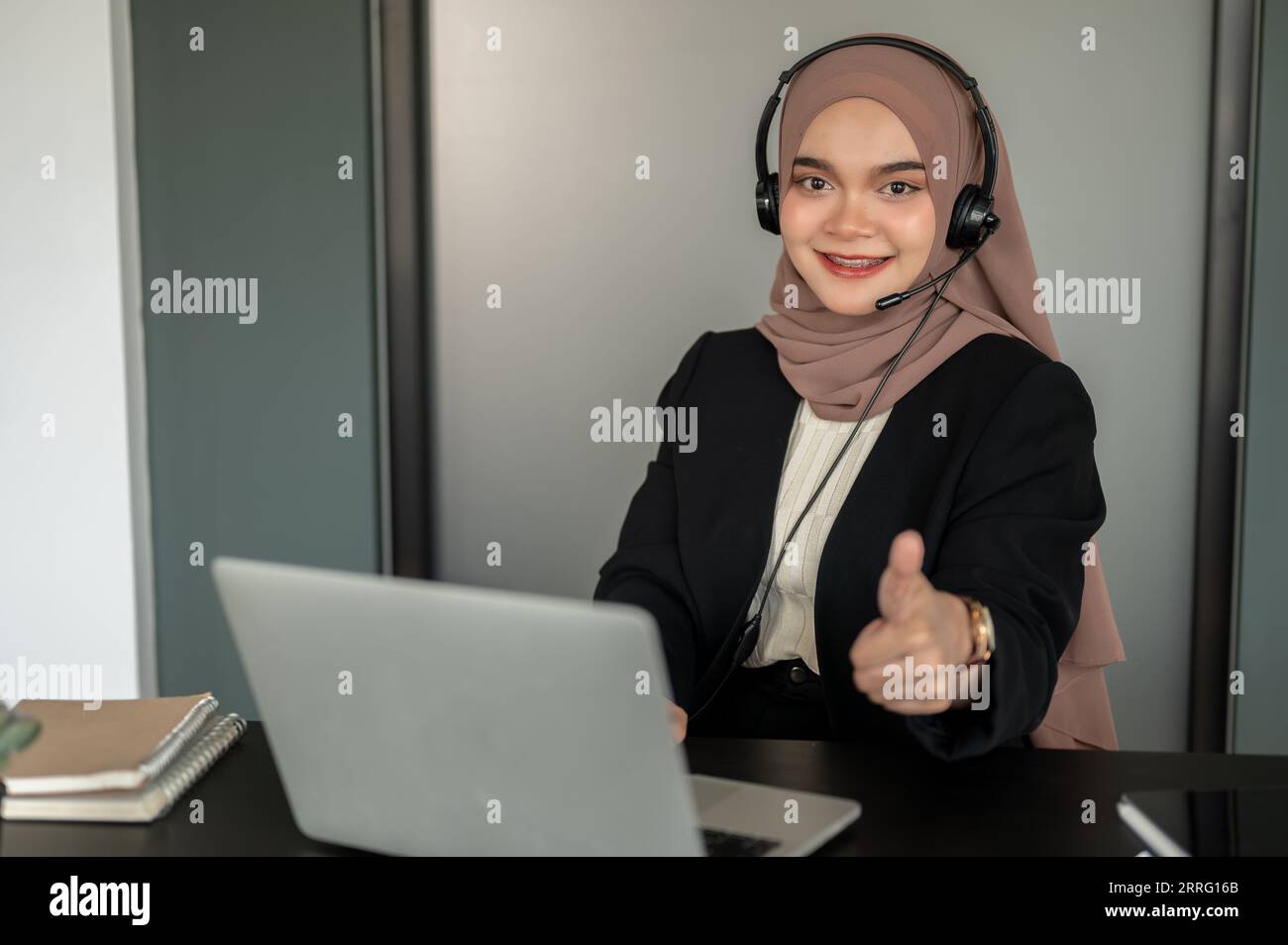 A cheerful Asian Muslim female sales agent or call centre operator ...