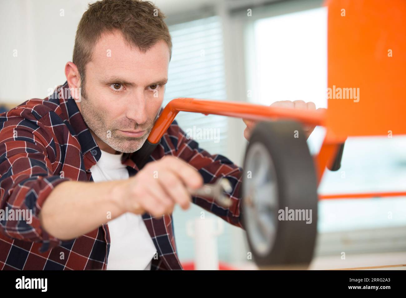 man tightening wheel nut on pallet truck Stock Photo - Alamy