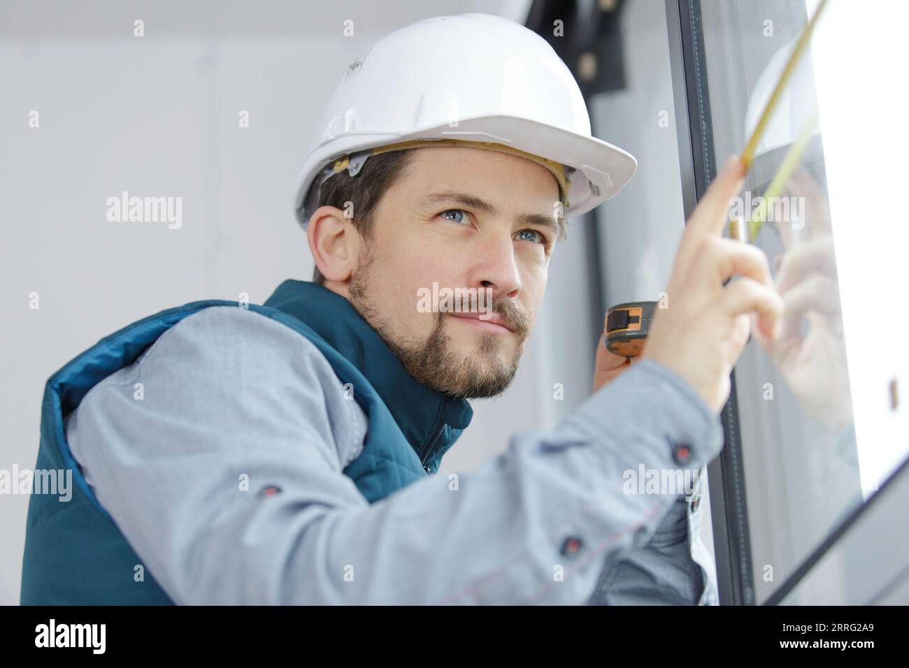 service man installing window with measure tape Stock Photo - Alamy