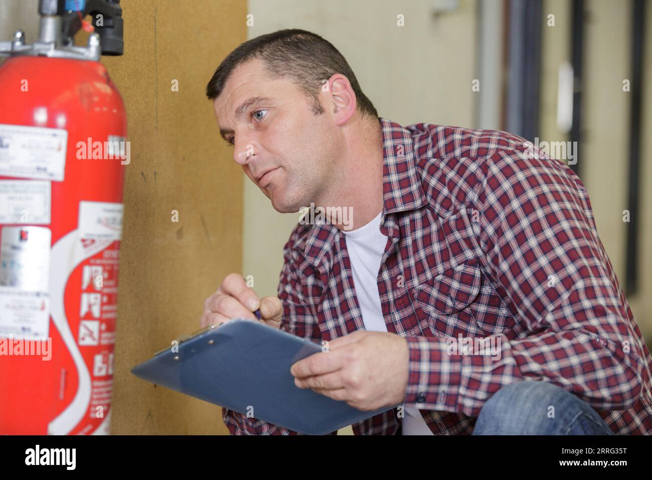 male professional checking a fire extinguisher using clipboard Stock ...