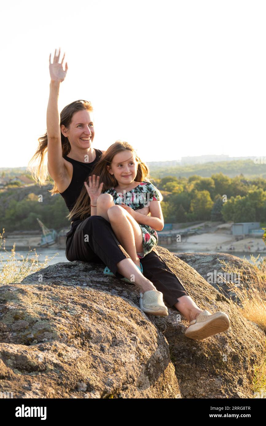 Mom and daughter waving to someone in nature, happy motherhood and ...