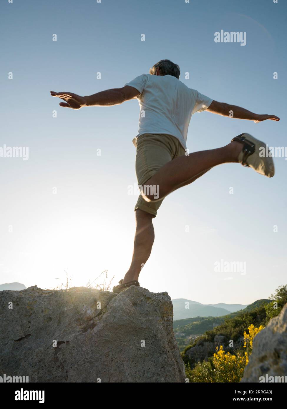 Man leaps onto rock above sea Stock Photo - Alamy