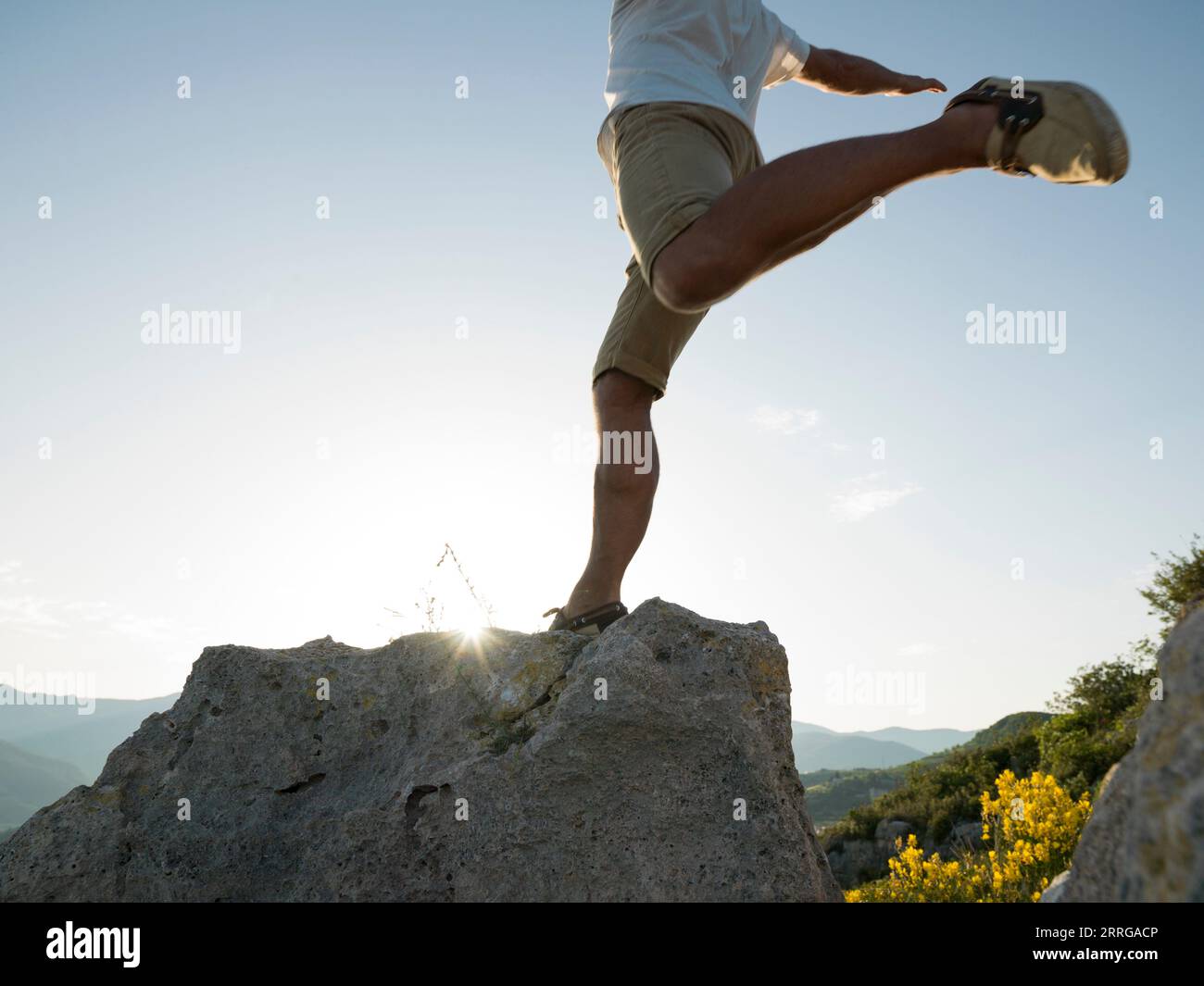 Man leaps onto rock above sea Stock Photo - Alamy