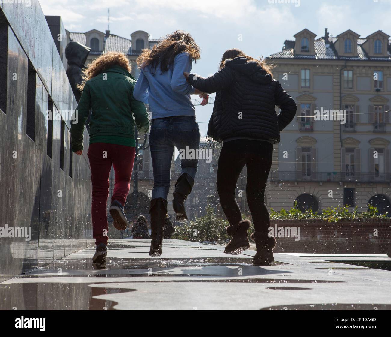 Teen girls splash through rain puddles in urban setting Stock Photo - Alamy