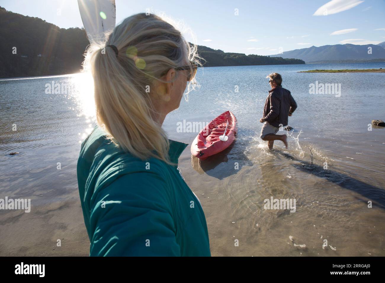 View past woman holding paddle to man running to kayak in lake Stock ...