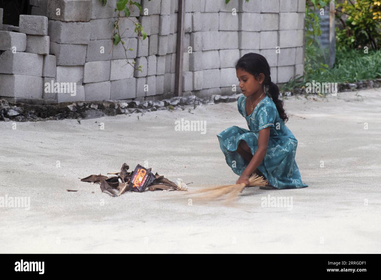 Cute little girl sweeping up trash outside Stock Photo - Alamy