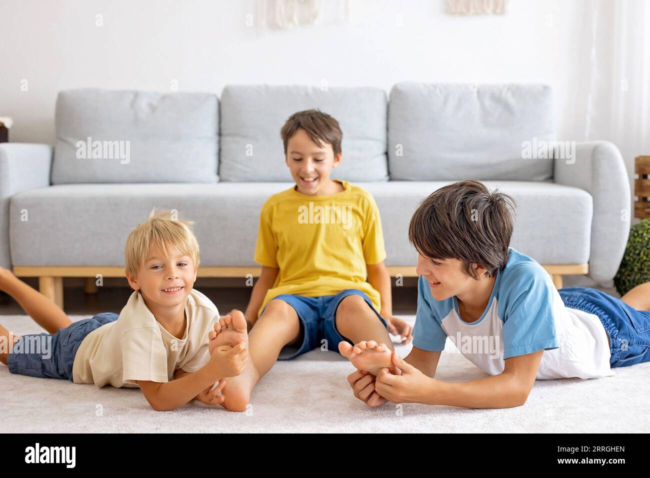 Happy positive children, tickling on the feet, having fun together, boy brothers at home having ...