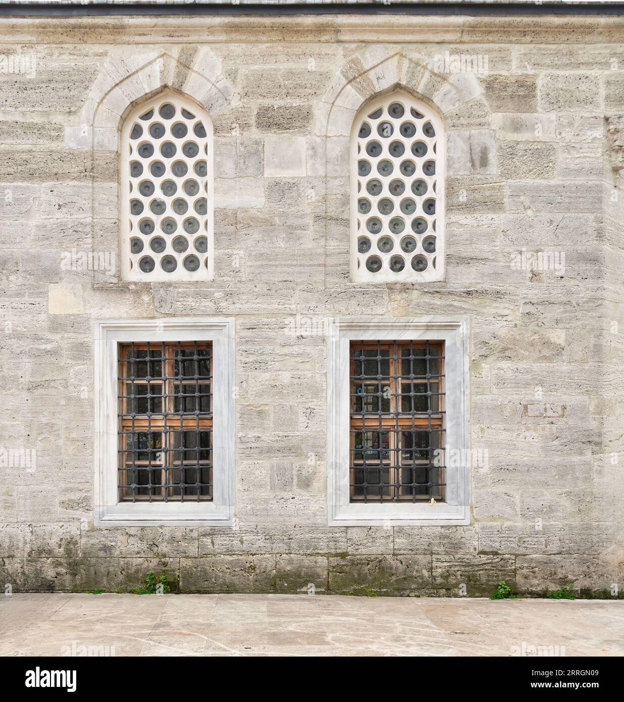Two perforated arched stucco windows and two windows with wrought iron ...