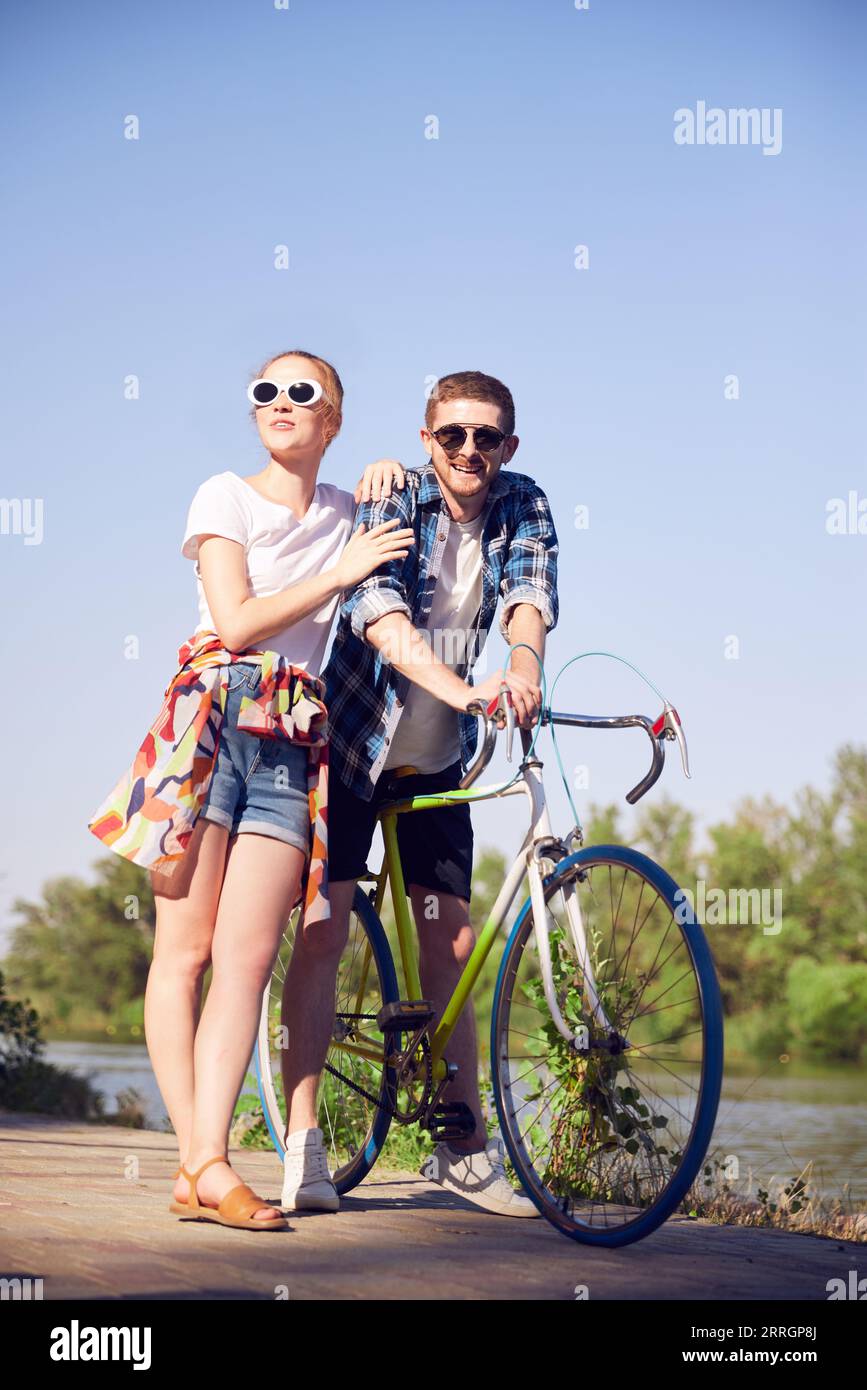 Attractive woman with her boyfriend enjoying riding a bicycle outdoor ...