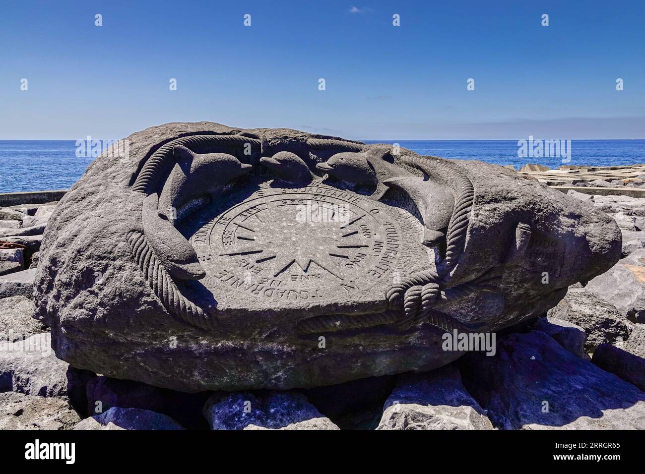 A giant rock carved into a compass with dolphins on the breakwater ...