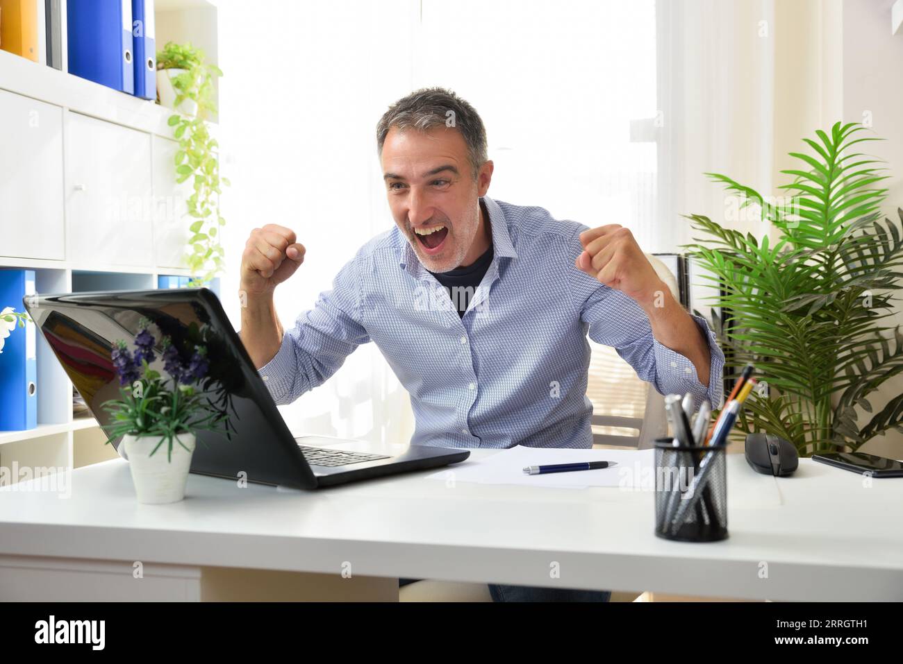 Euphoric entrepreneur man celebrating work success in his home office ...