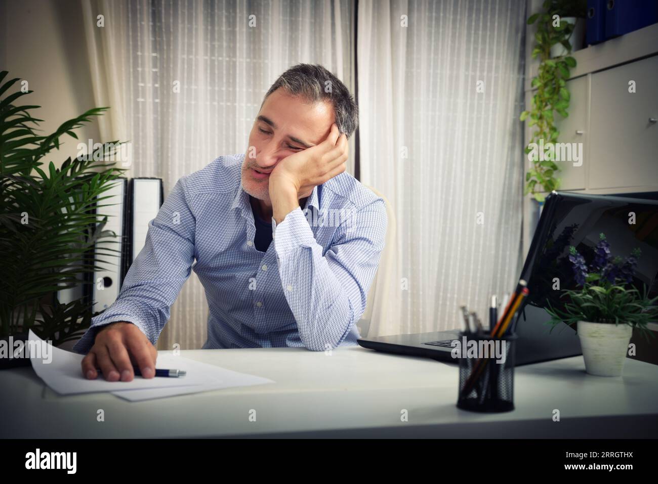 Exhausted office worker asleep leaning with palm on face and elbow on ...