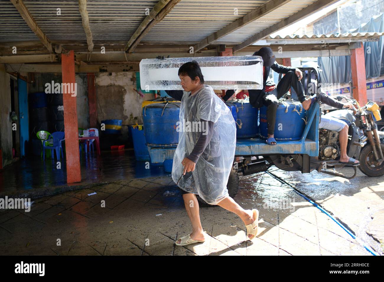 Ethnic man carrying a block of ice on the street Stock Photo - Alamy