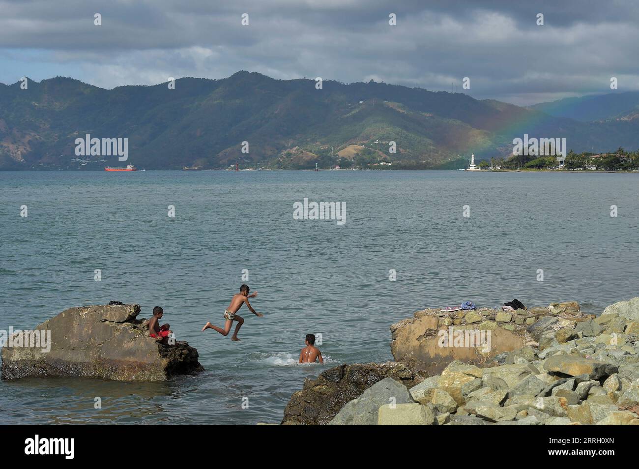 220606 -- DILI, June 6, 2022 -- Children play in the sea as rainbow ...